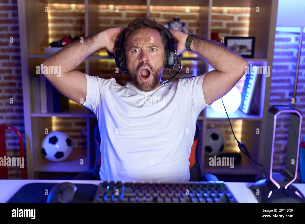 Middle age man with beard playing video games wearing headphones crazy ...