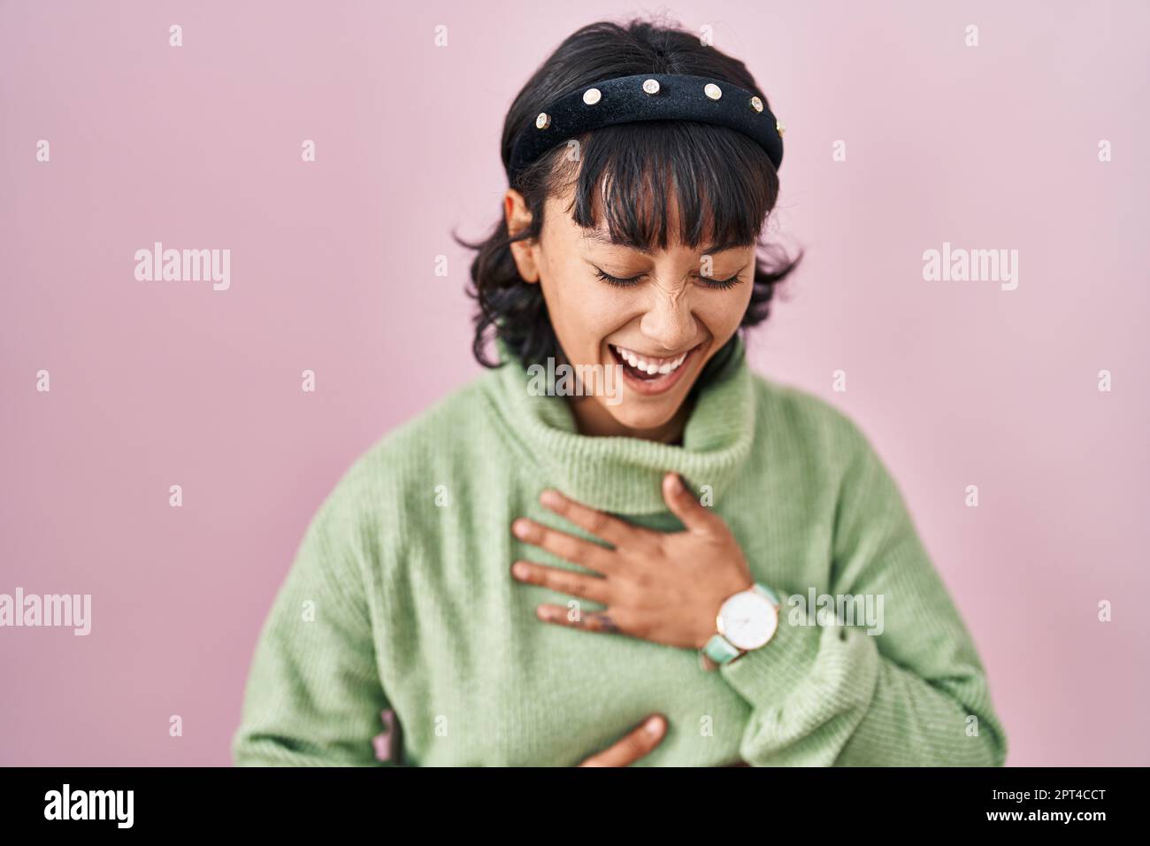 Young beautiful woman standing over pink background smiling and ...