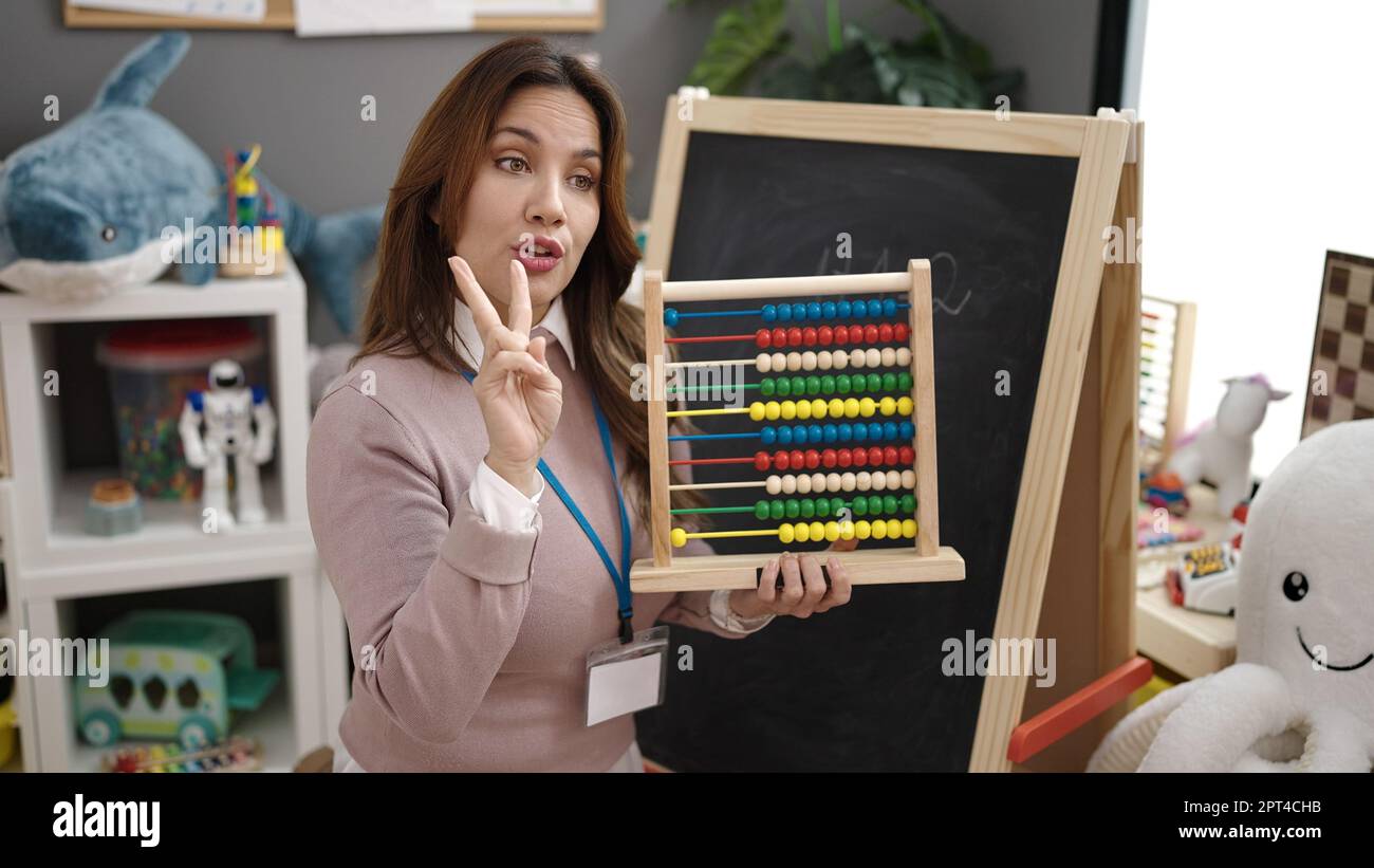 Young beautiful hispanic woman preschool teacher explaining maths ...
