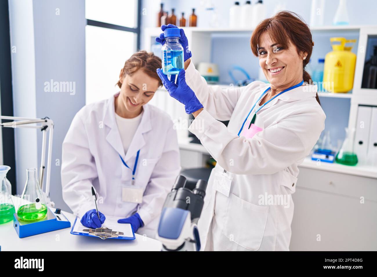 Two women scientists holding test tube writing on document at ...