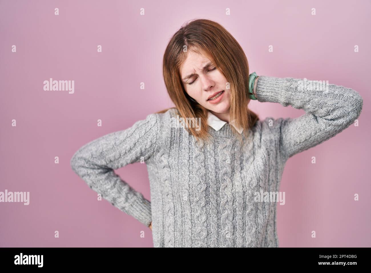 Beautiful woman standing over pink background suffering of neck ache ...
