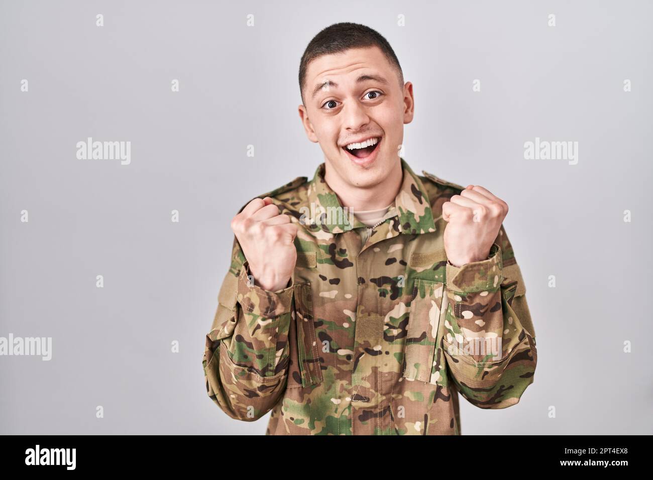 Young man wearing camouflage army uniform celebrating surprised and ...