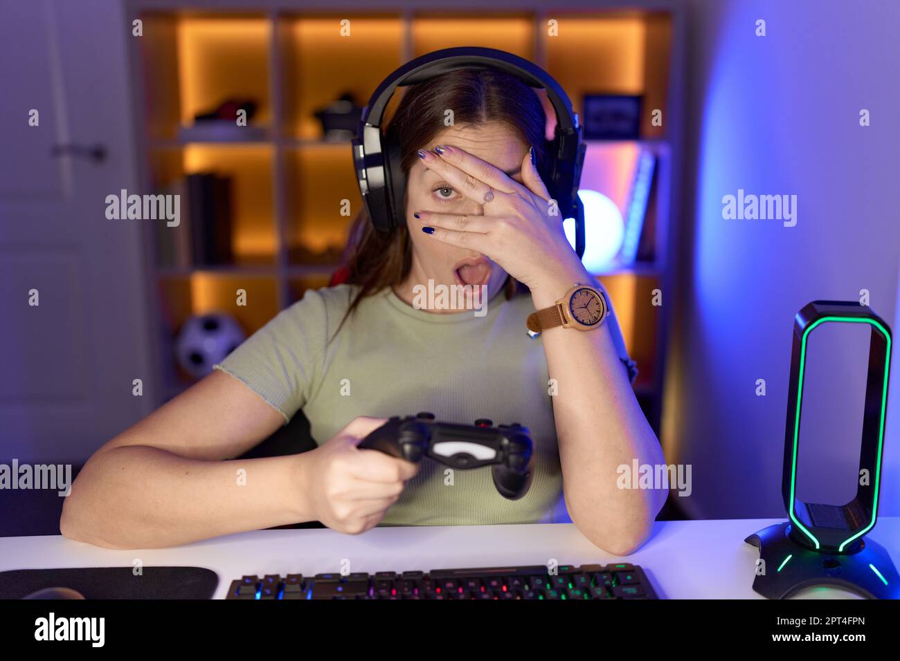 Beautiful brunette woman playing video games wearing headphones peeking ...