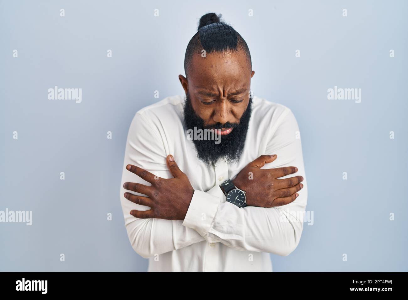 African american man standing over blue background shaking and freezing ...