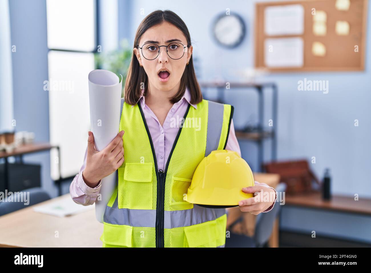 Hispanic girl architect holding build project blueprints in shock face ...