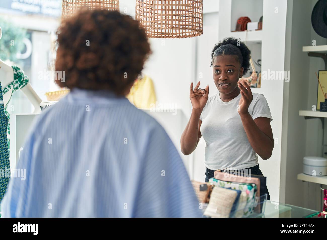 African american women shop assistant and customer speaking at clothing ...