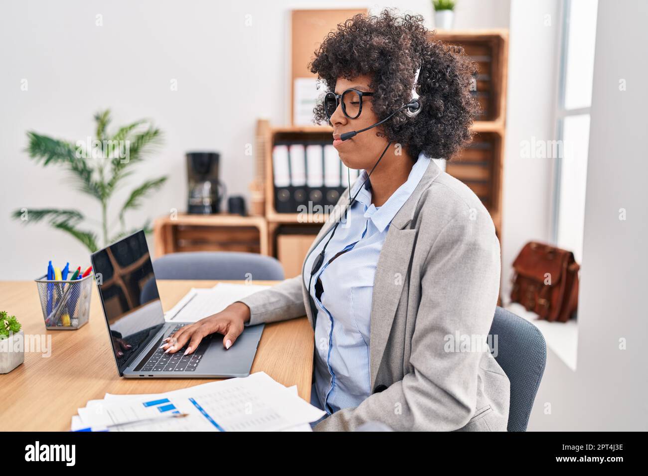 Black woman with curly hair wearing call center agent headset at the ...