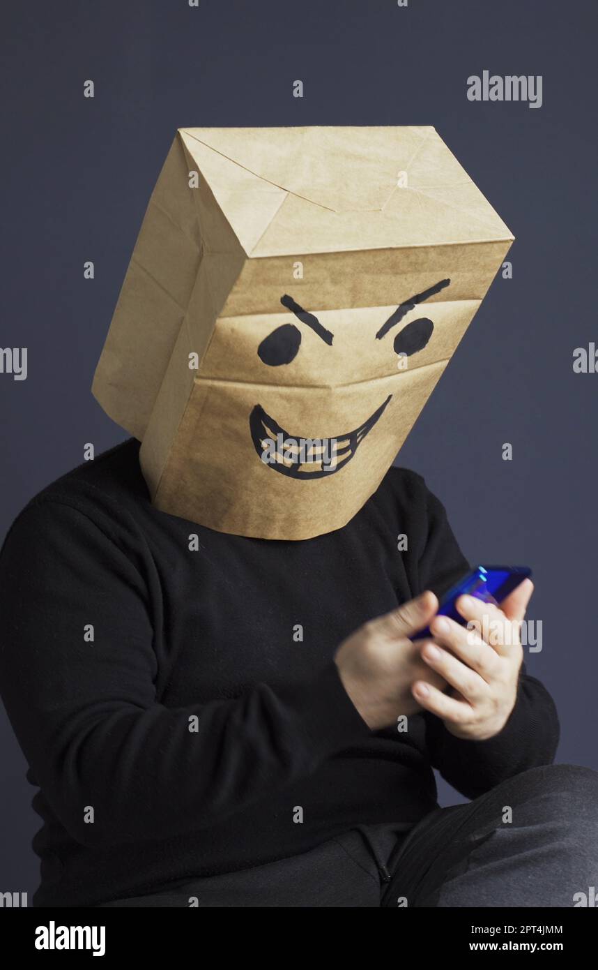 A man in a black turtleneck with a paper bag with an angry emoji on his ...