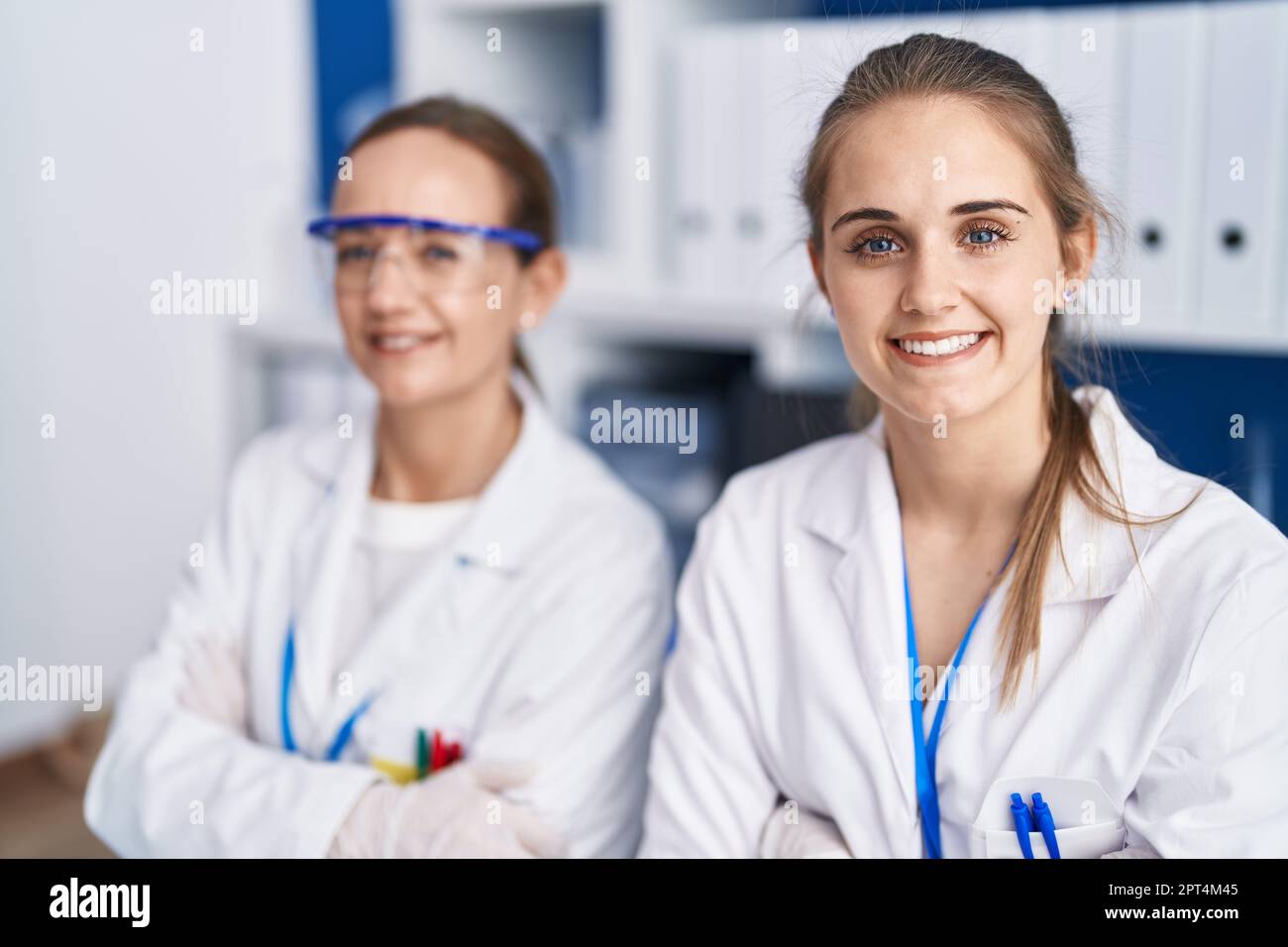 Two women scientists smiling confident with arms crossed gesture at ...