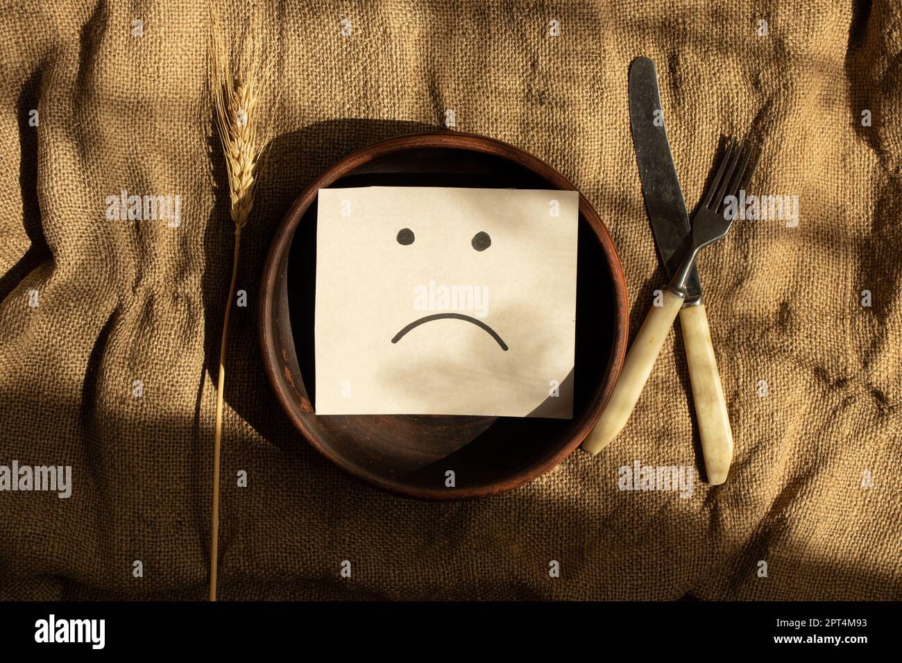 A sad smile is drawn on a card that lies in a clay plate on the table ...