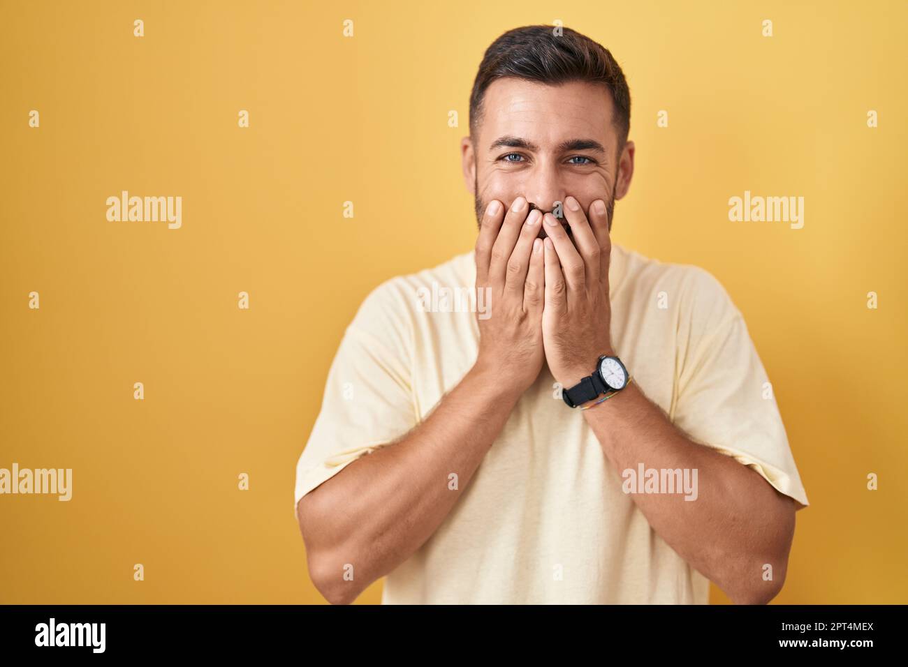 Handsome hispanic man standing over yellow background laughing and ...