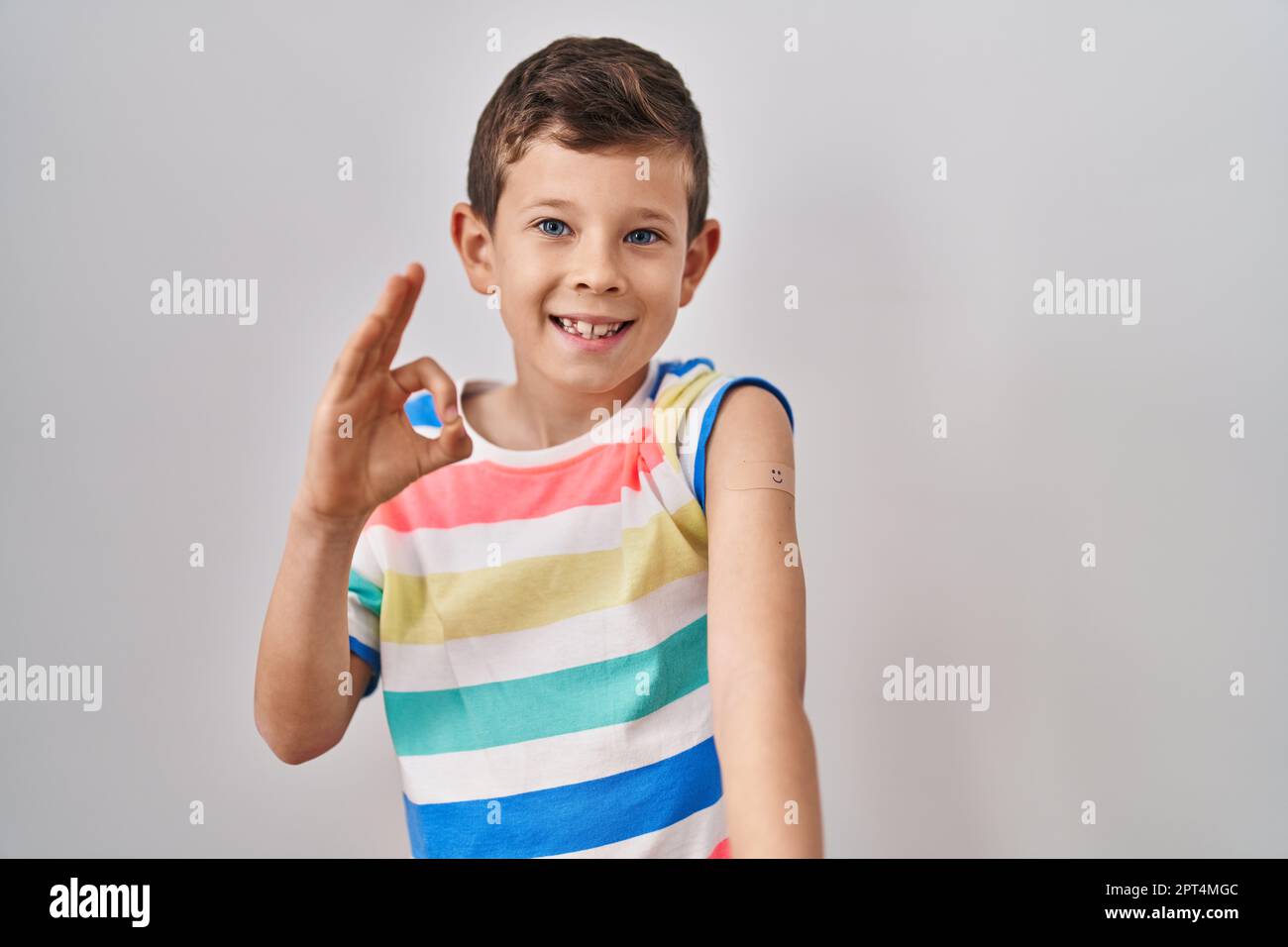 Young caucasian kid getting vaccine showing arm with band aid doing ok ...
