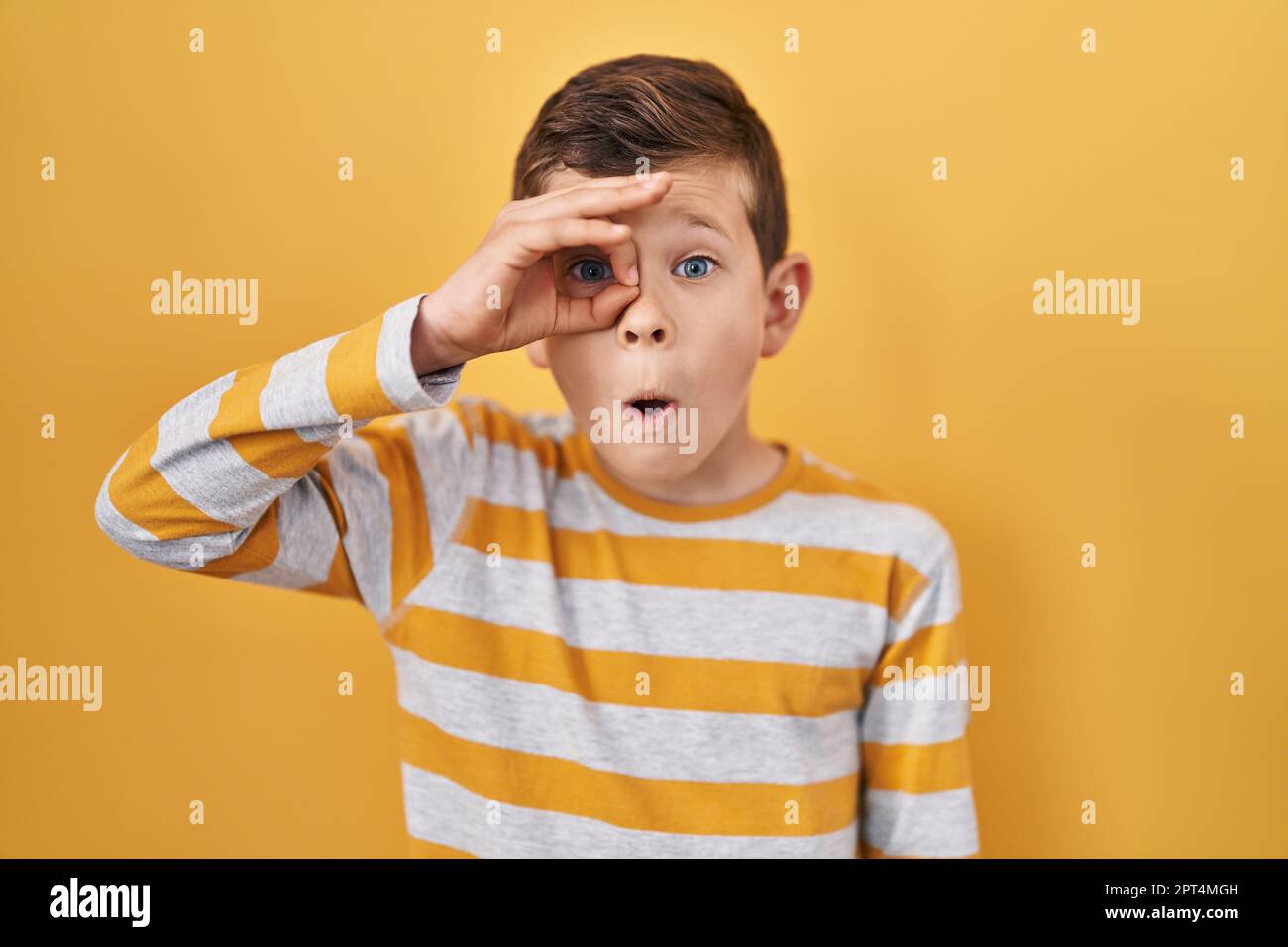 Young caucasian kid standing over yellow background doing ok gesture ...
