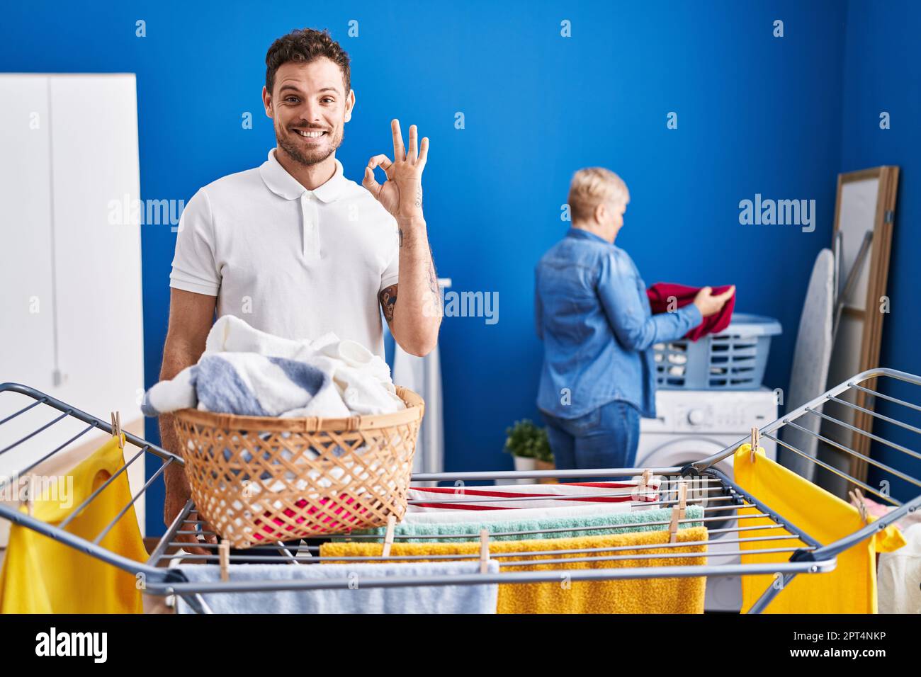 Hispanic mother and son hanging clothes at clothesline doing ok sign ...