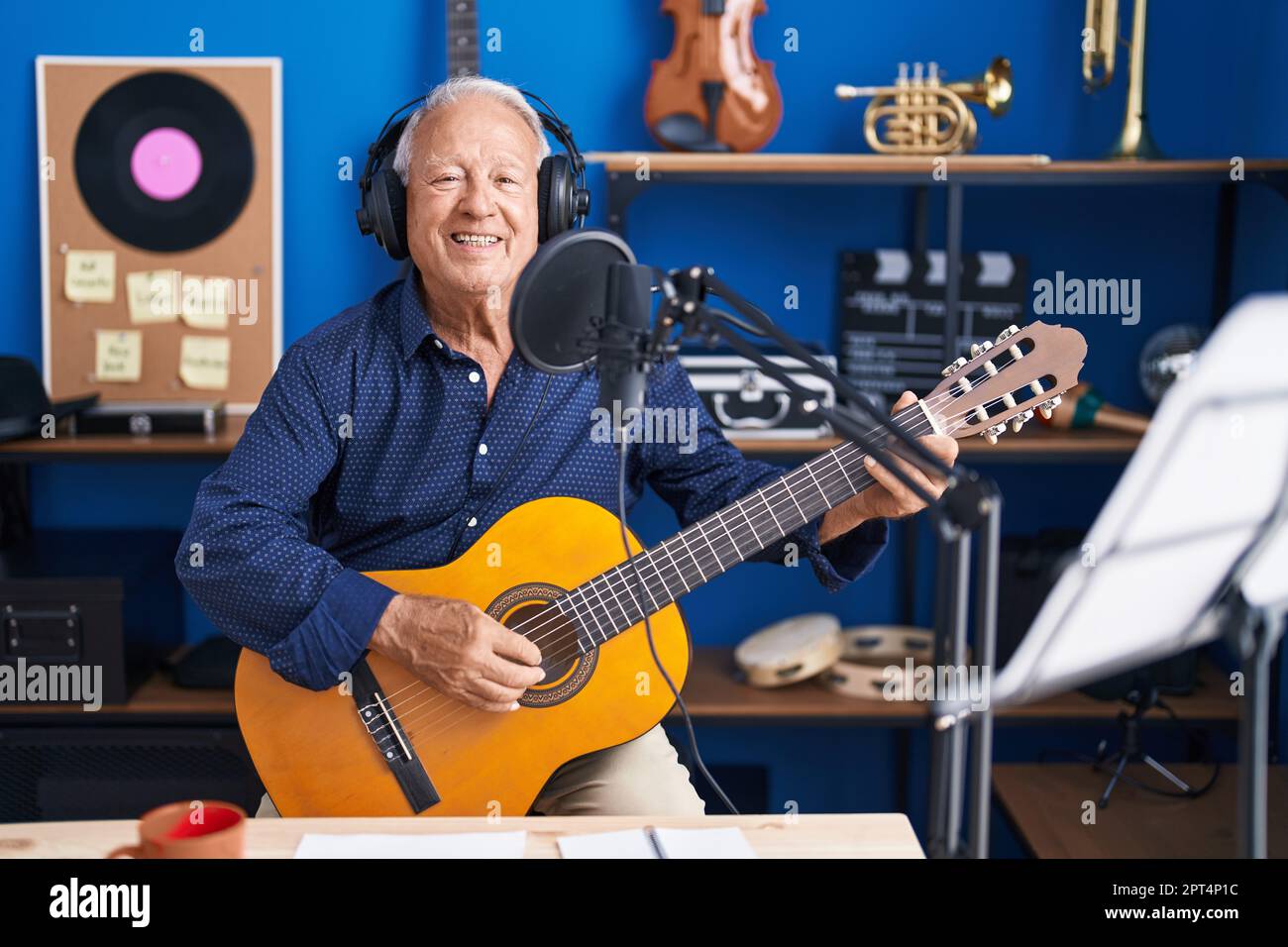 Senior grey-haired man musician singing song playing guitar at music ...