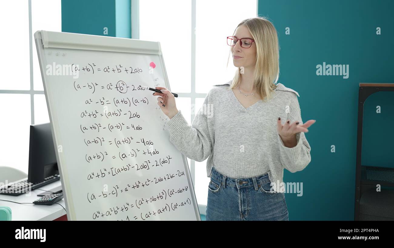 Young blonde woman teaching maths on magnetic board at library ...