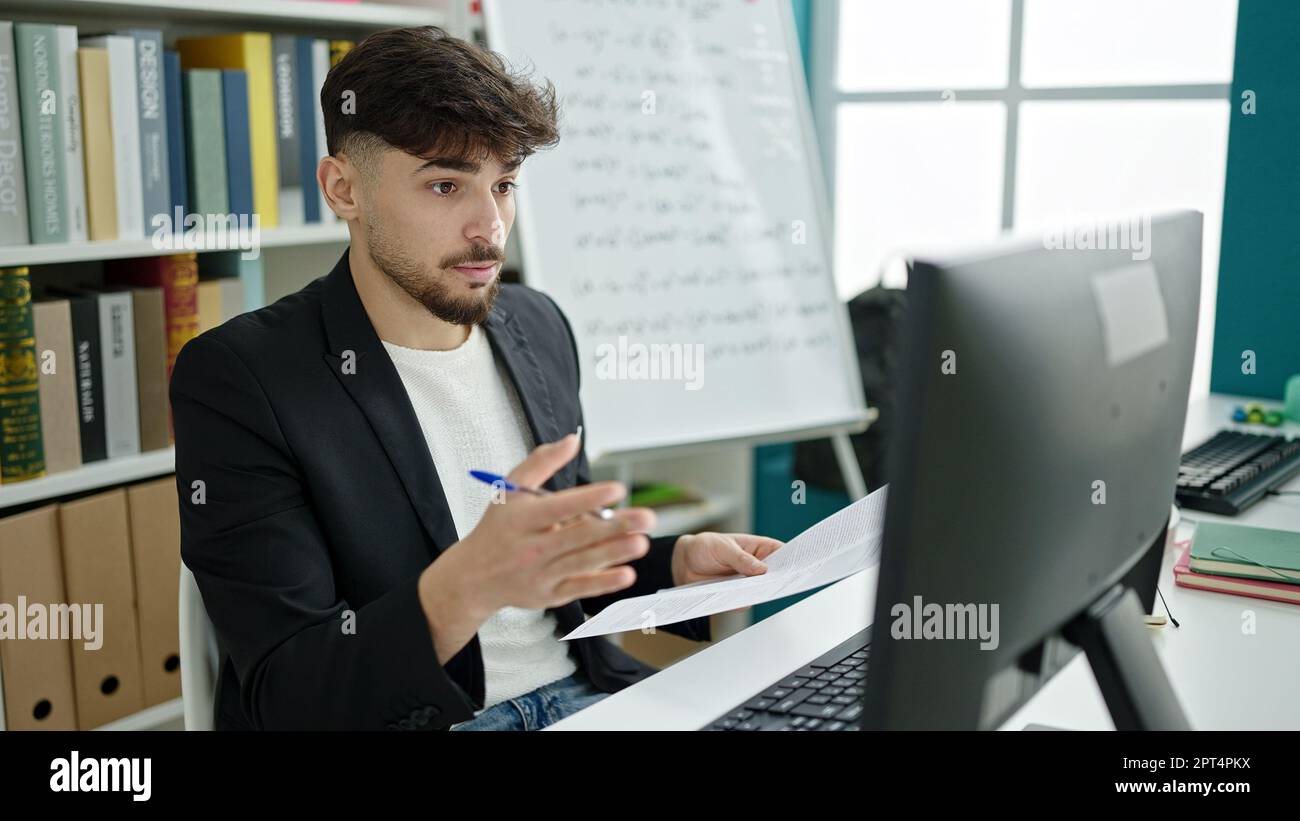 Young arab man student using computer reading document at university ...