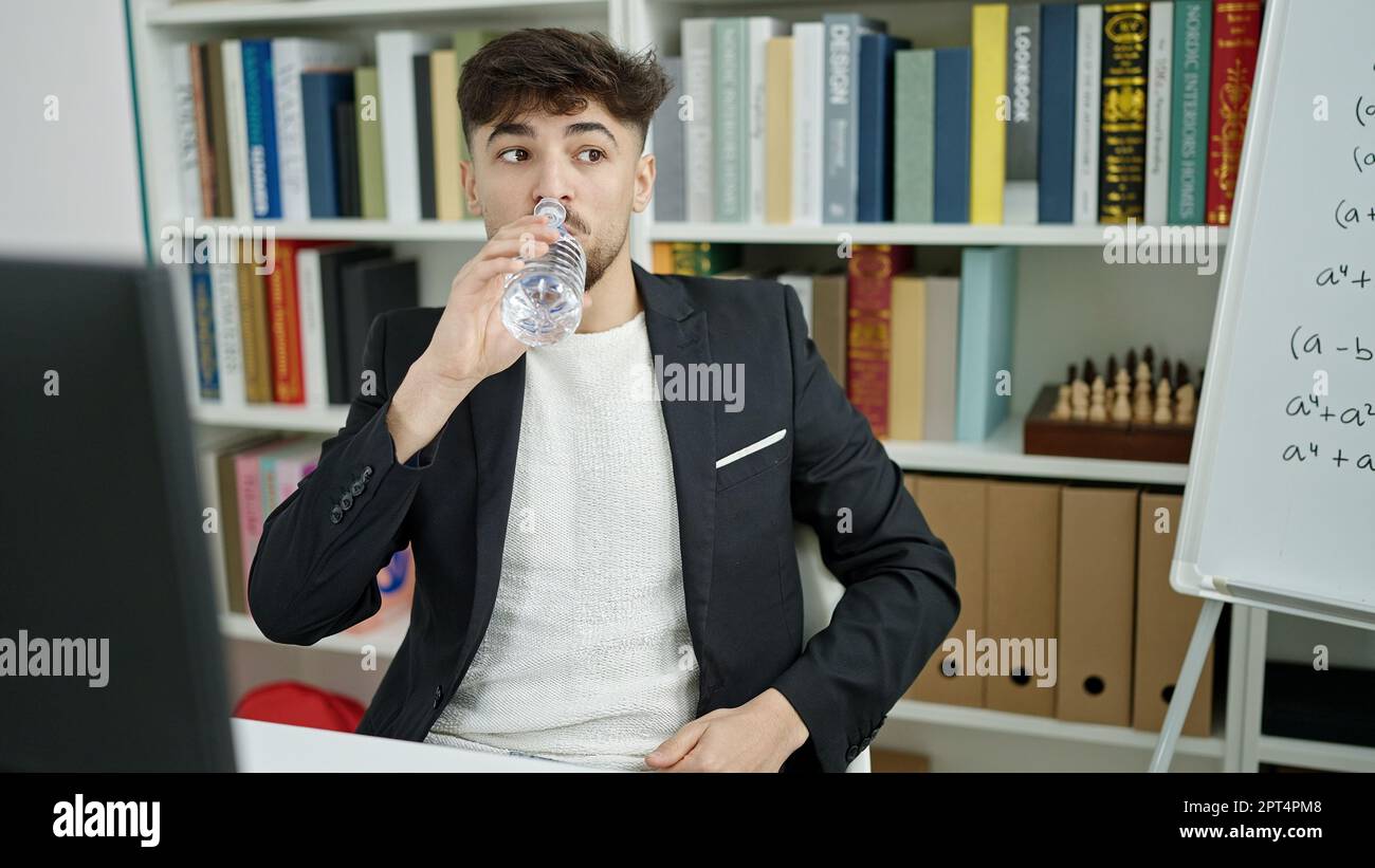 Young arab man student drinking water at university classroom Stock ...