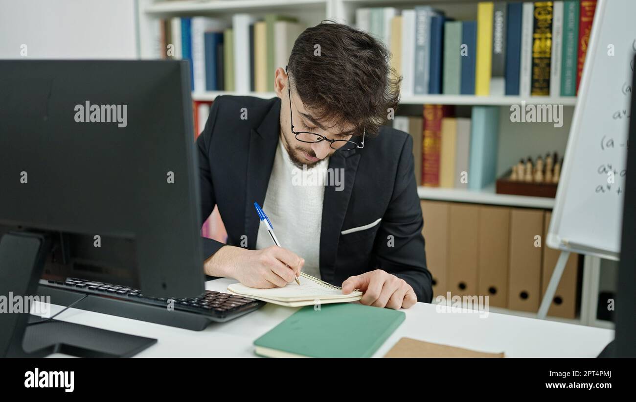Young arab man student using computer writing on notebook at university ...