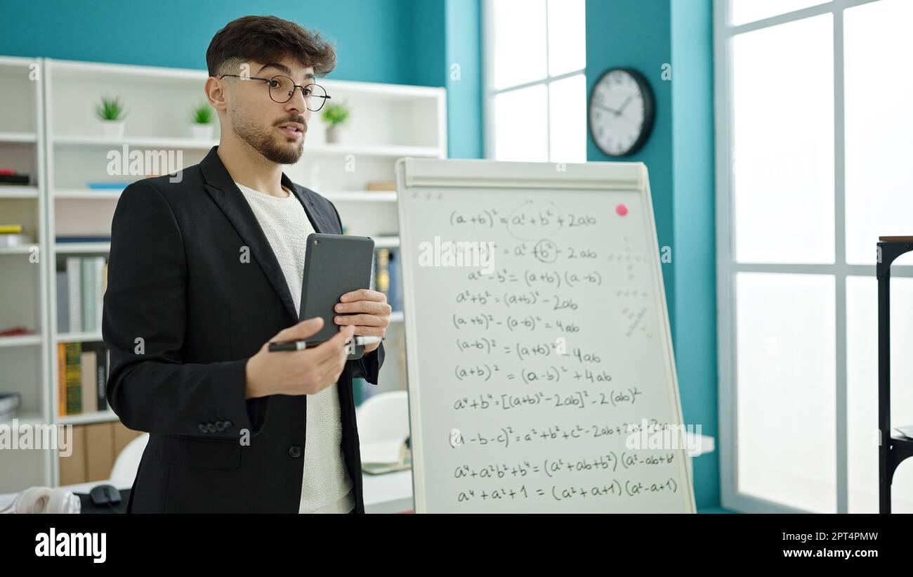 Young arab man teacher teaching maths lesson using touchpad at ...