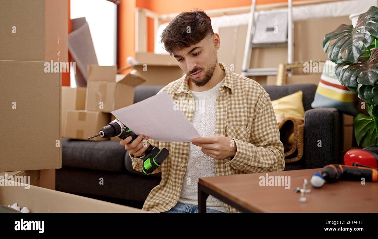 Young arab man repairing table reading instructions at new home Stock ...
