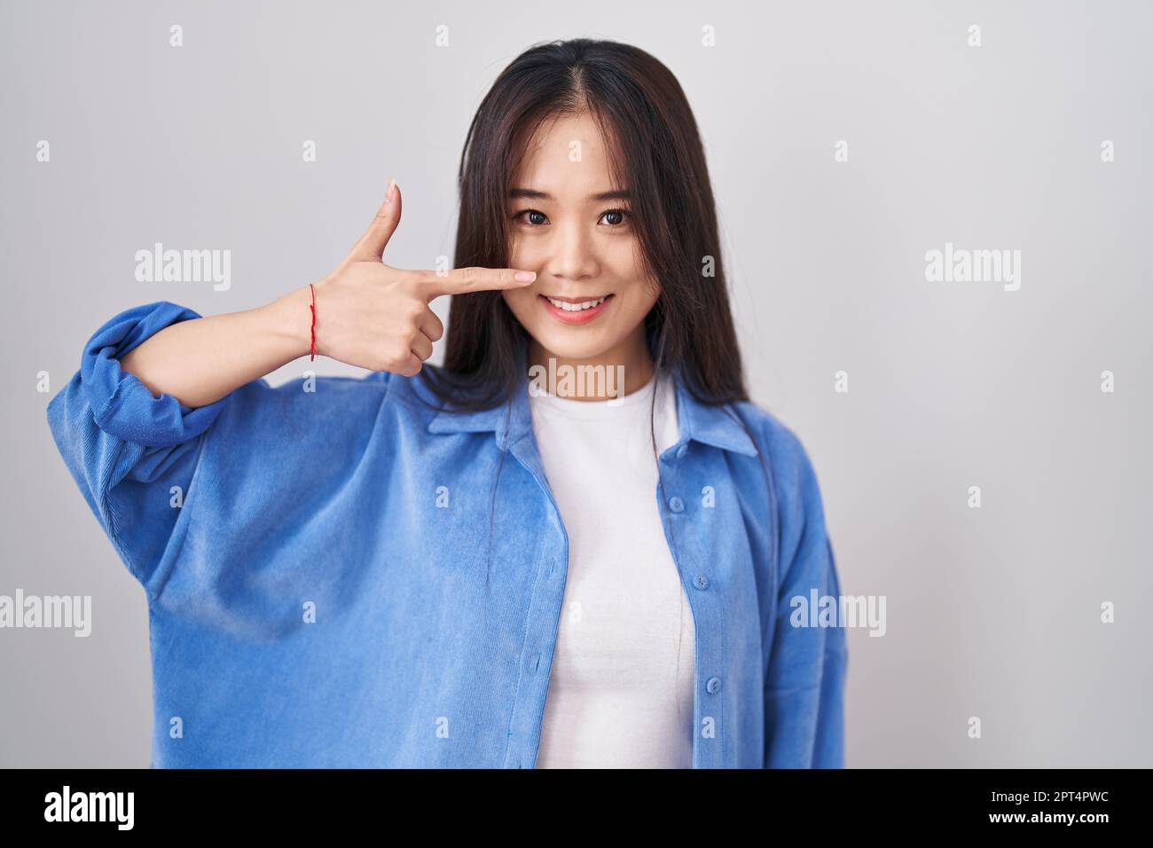 Young chinese woman standing over white background pointing with hand ...
