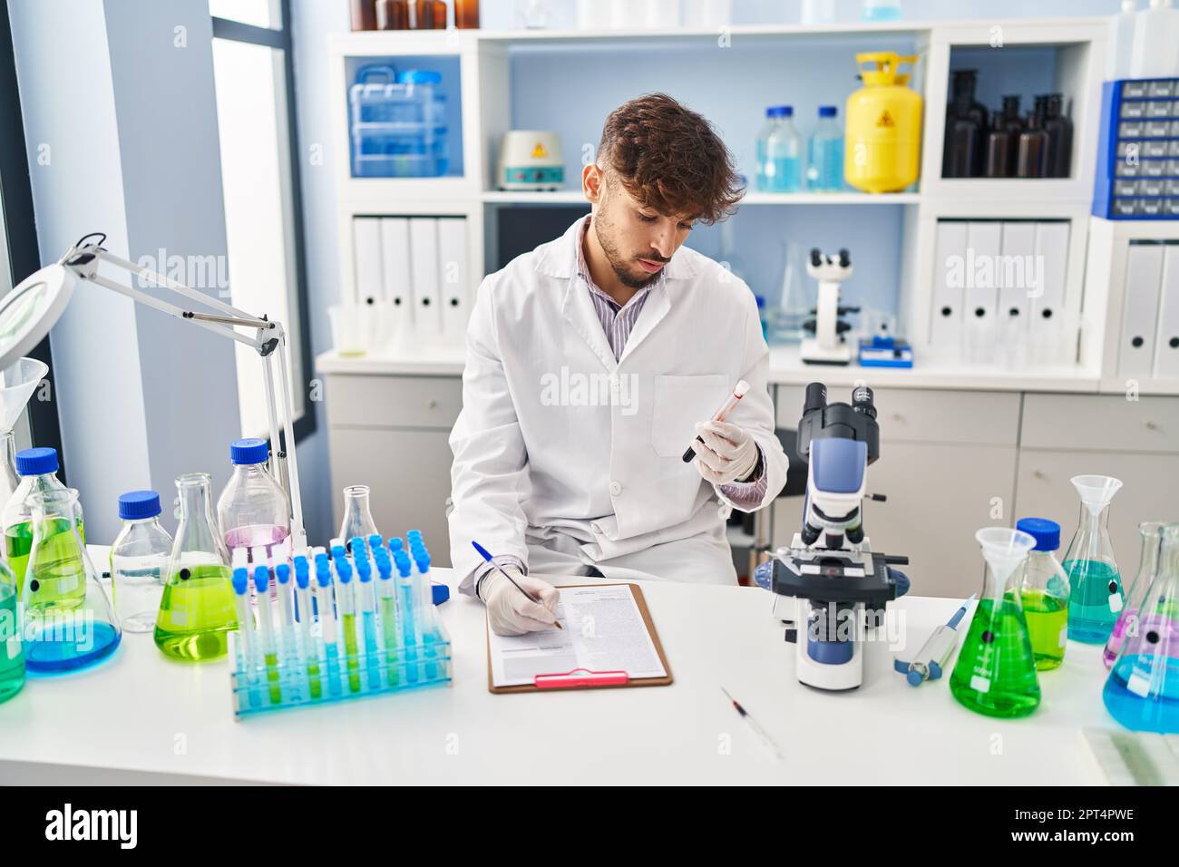Young arab man scientist write on document analysing blood test tube at ...