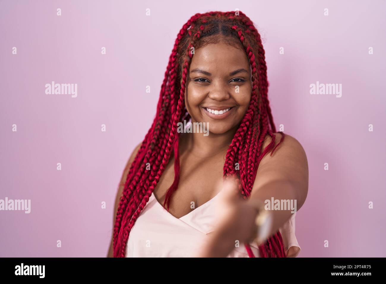 African american woman with braided hair standing over pink background ...