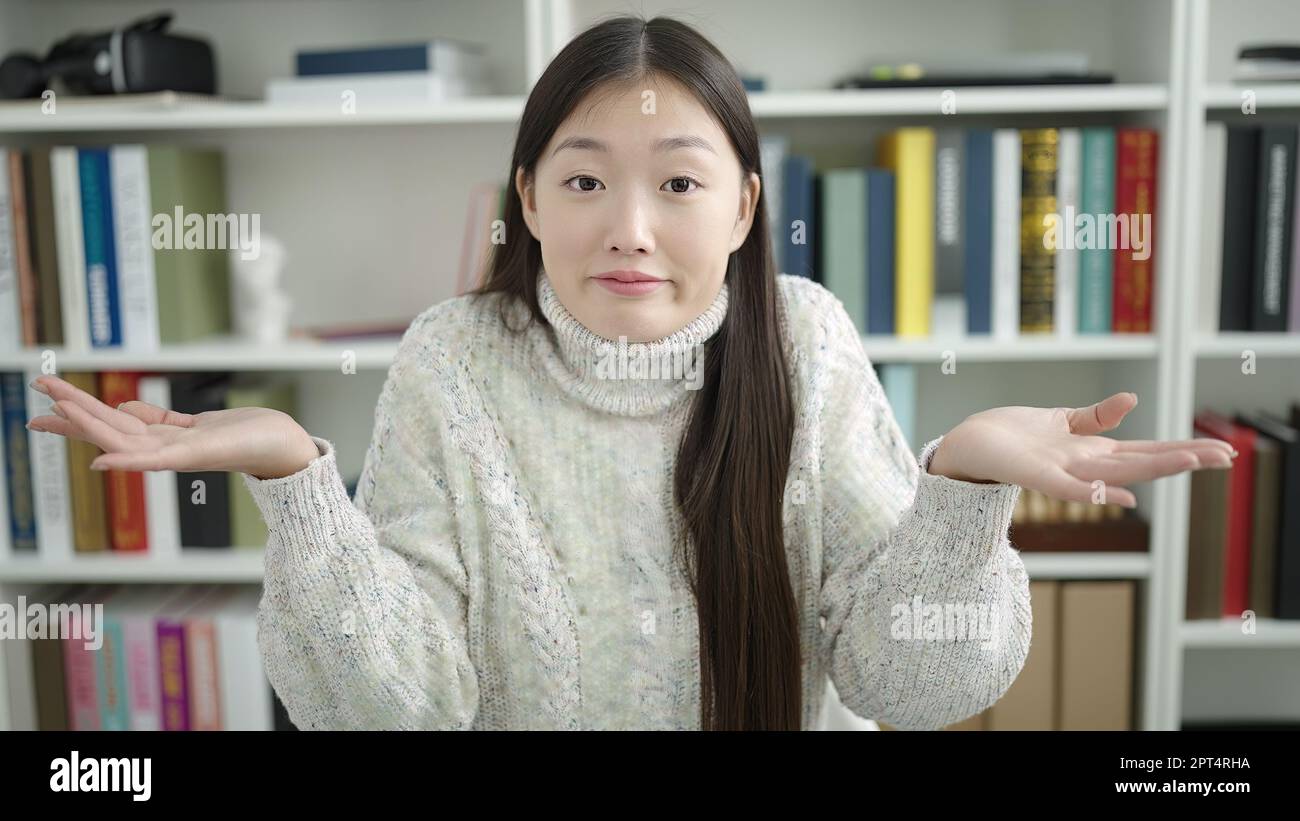 Young chinese woman student standing with i dont know expression at ...