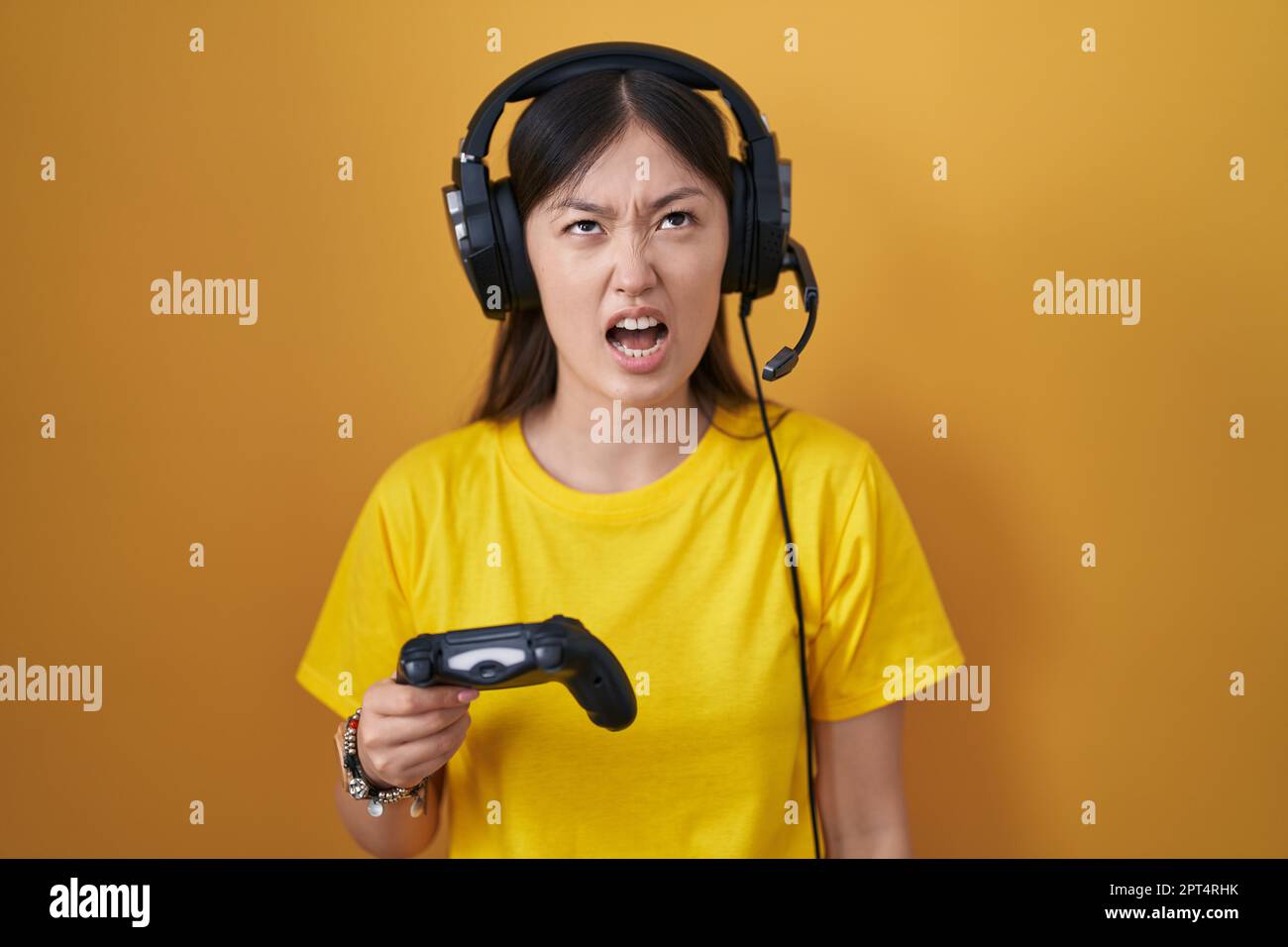 Chinese young woman playing video game holding controller angry and mad ...