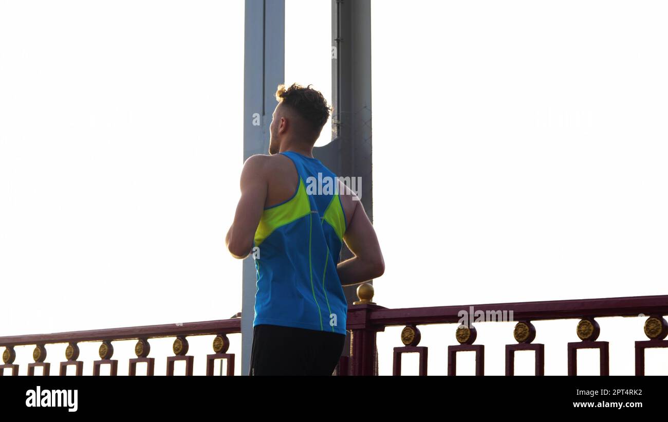 Rear of male athlete working out running outdoors alone. Sport workout ...