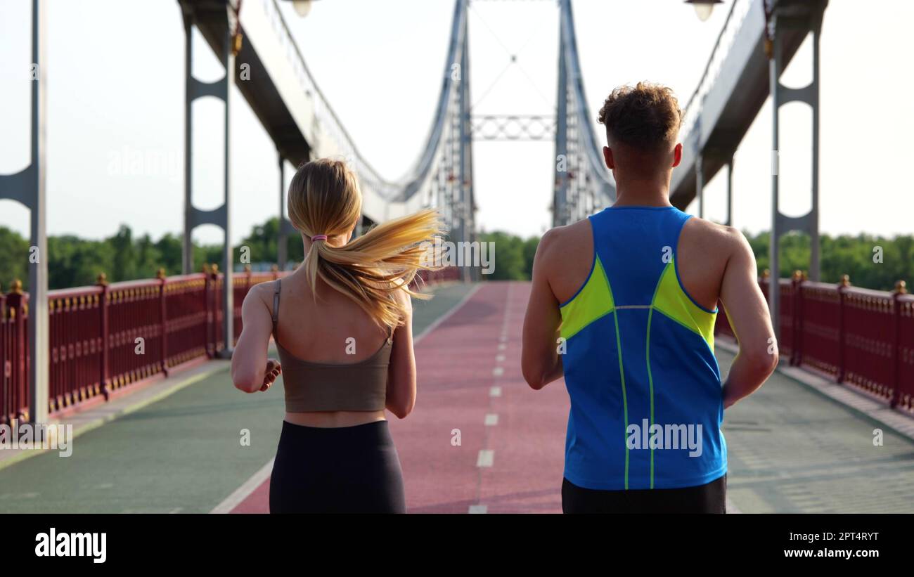 Back view of Caucasian young couple of friends running together working ...