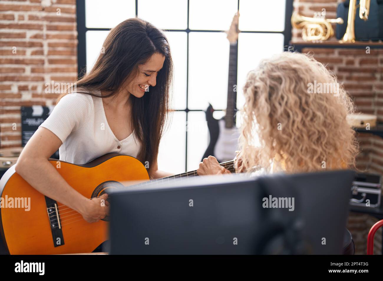 Two women musicians having classical guitar lesson at music studio ...