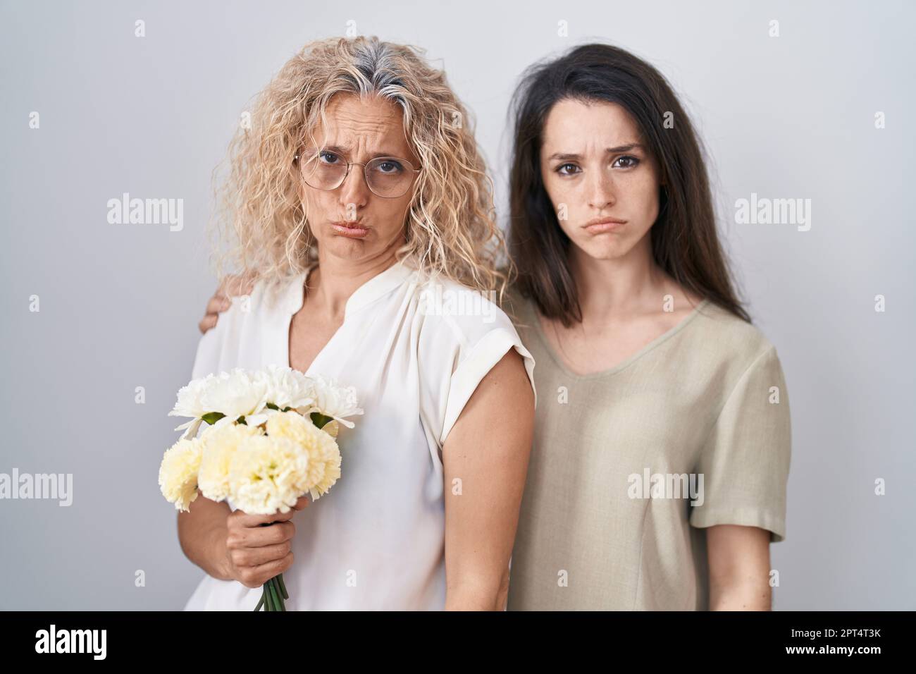 Mother and daughter holding bouquet of white flowers depressed and ...