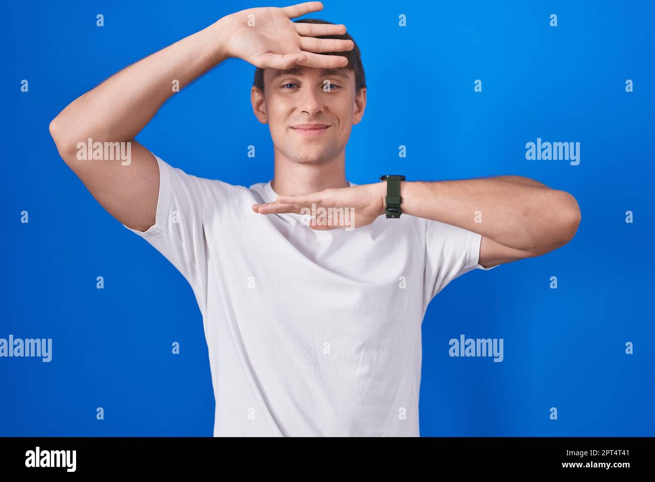 Caucasian blond man standing over blue background smiling cheerful ...