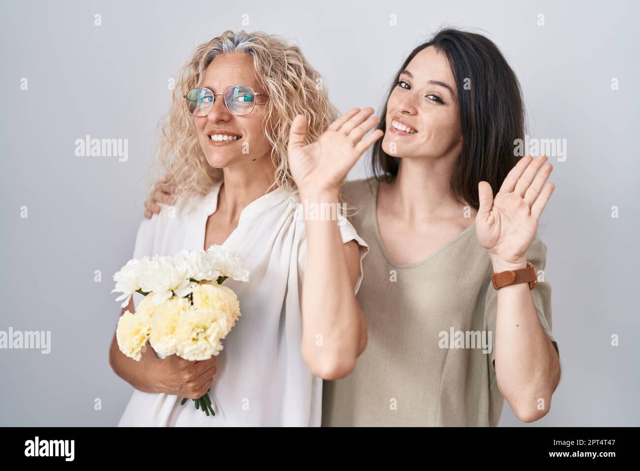 Mother and daughter holding bouquet of white flowers waiving saying ...