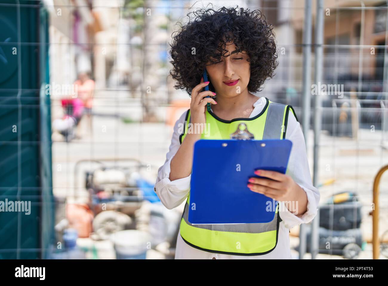 Young middle east woman architect talking on smartphone reading ...