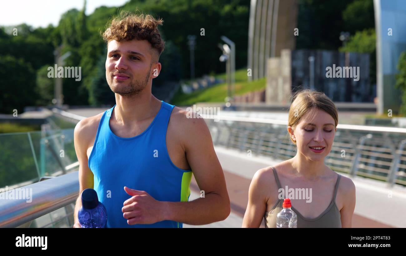 Handsome man and beautiful woman working out on street running together ...