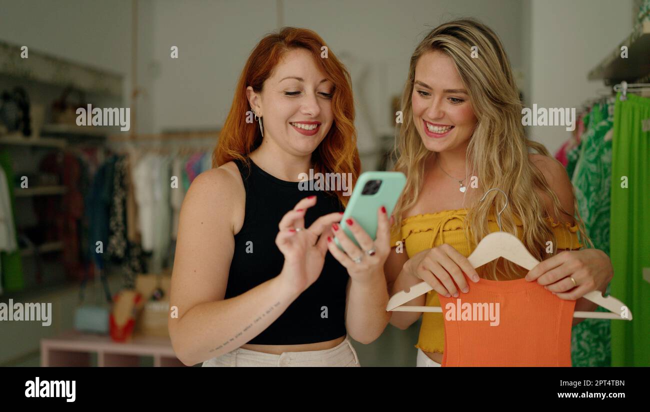 Two women using smartphone shopping at clothing store Stock Photo - Alamy