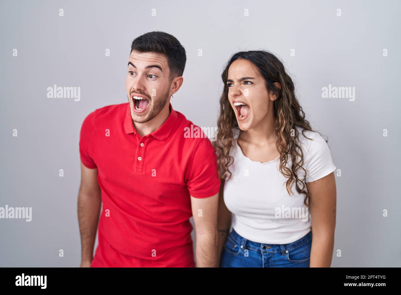 Young hispanic couple standing over isolated background angry and mad ...