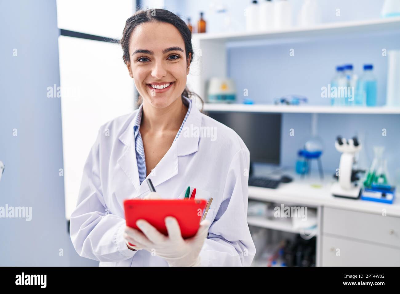 Young hispanic woman wearing scientist uniform using touchpad at laboratory Stock Photo - Alamy