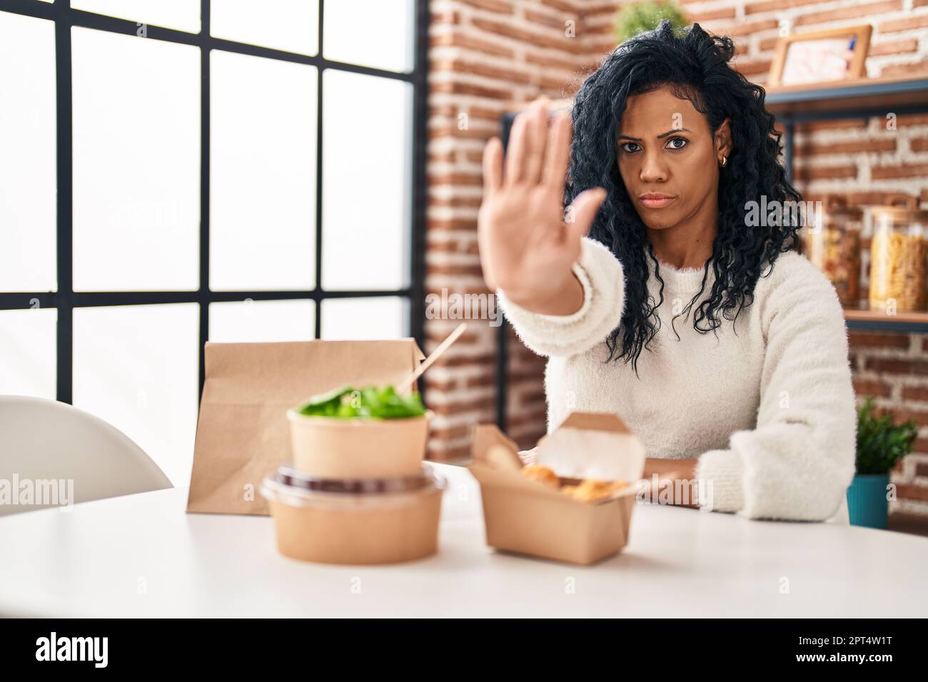 Middle age hispanic woman eating take away food with open hand doing ...