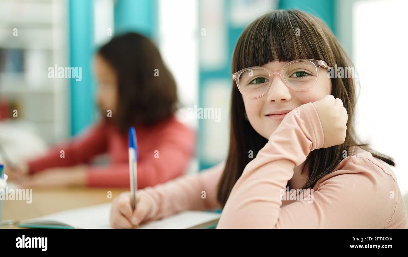 Adorable hispanic girl student writing on notebook at classroom Stock ... Adorable hispanic girl student writing on notebook at classroom Stock ...