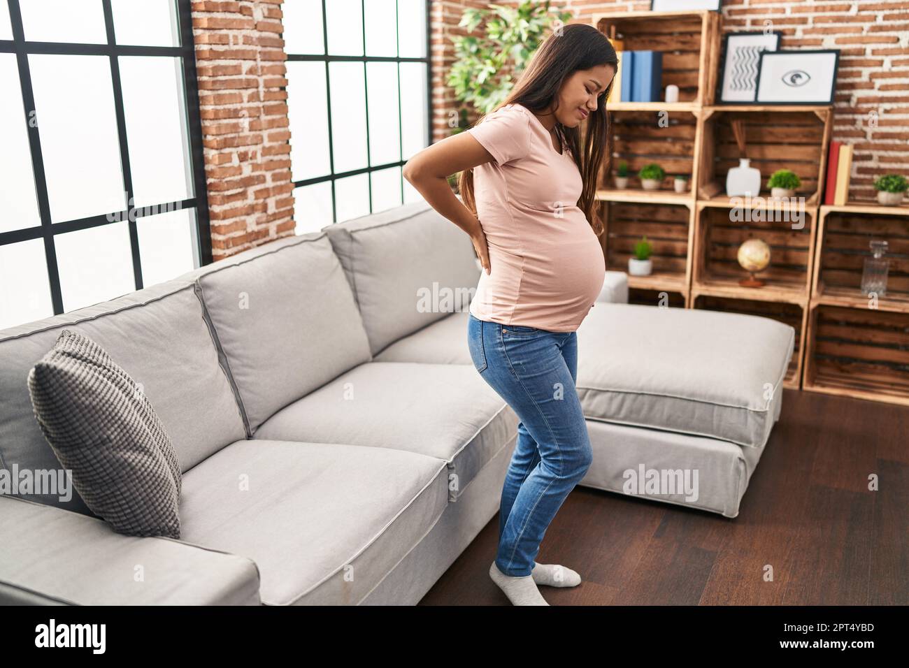 Young latin woman pregnant suffering for back and belly pain at home ...