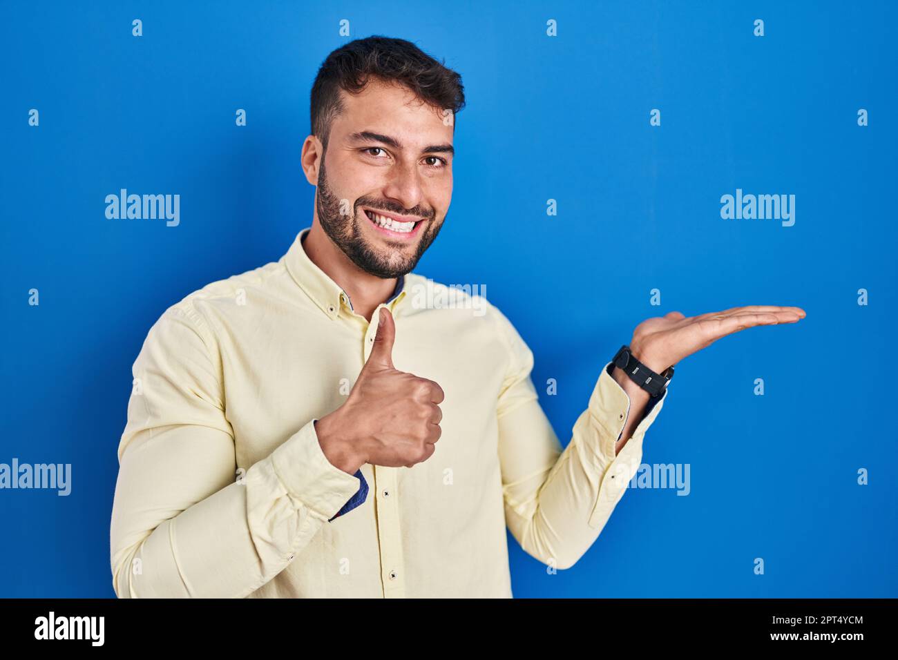 Handsome hispanic man standing over blue background showing palm hand ...