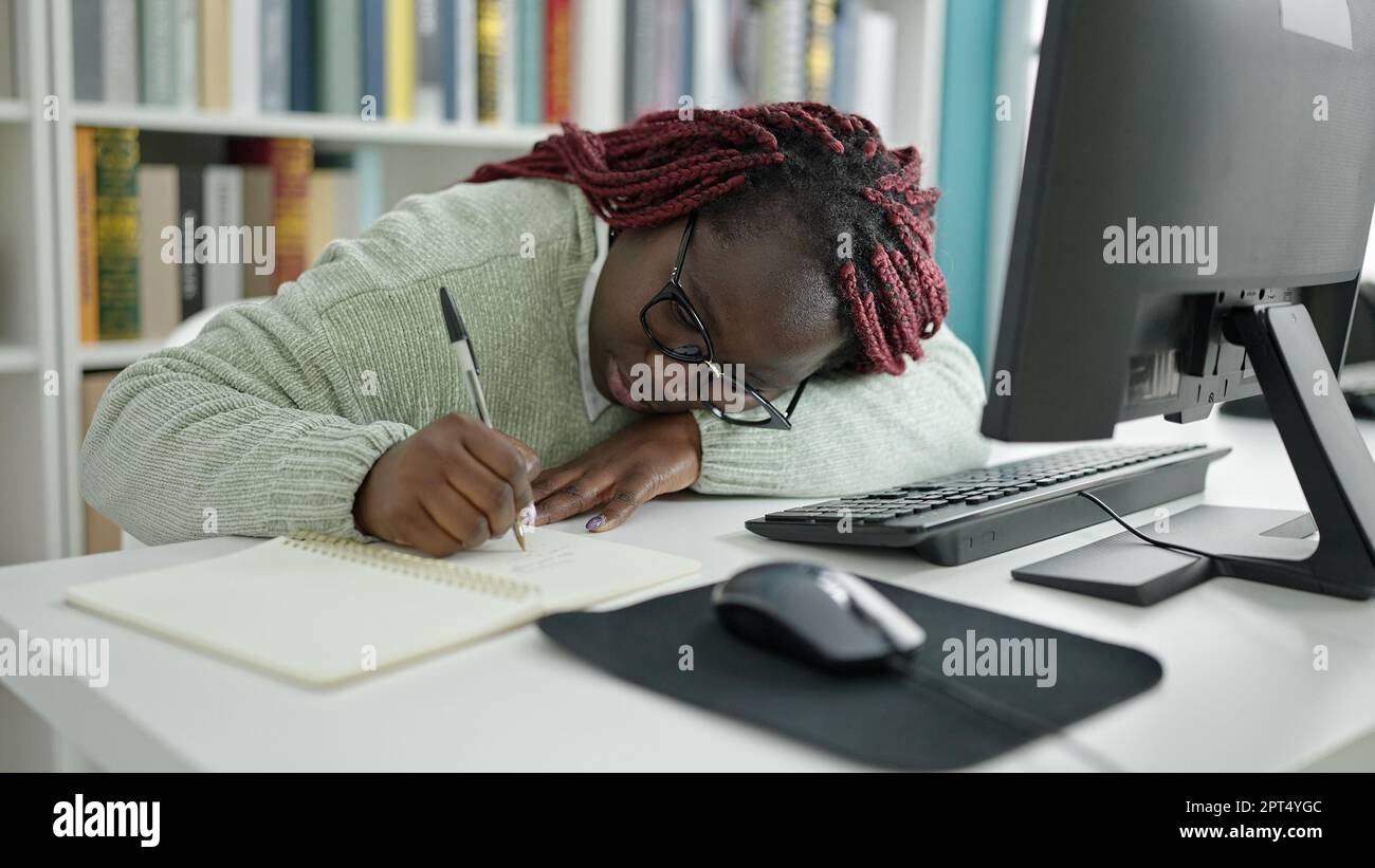 African woman with braided hair student writing notes tired at ...