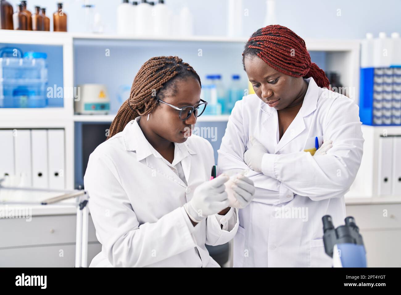African american women scientists looking sample standing with arms crossed gesture at ...