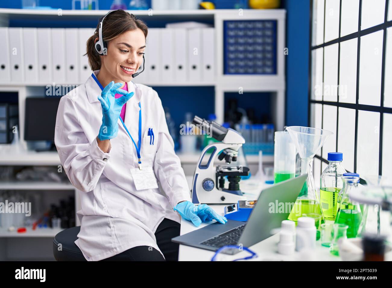 Hispanic woman working at scientist laboratory doing ok sign with ...