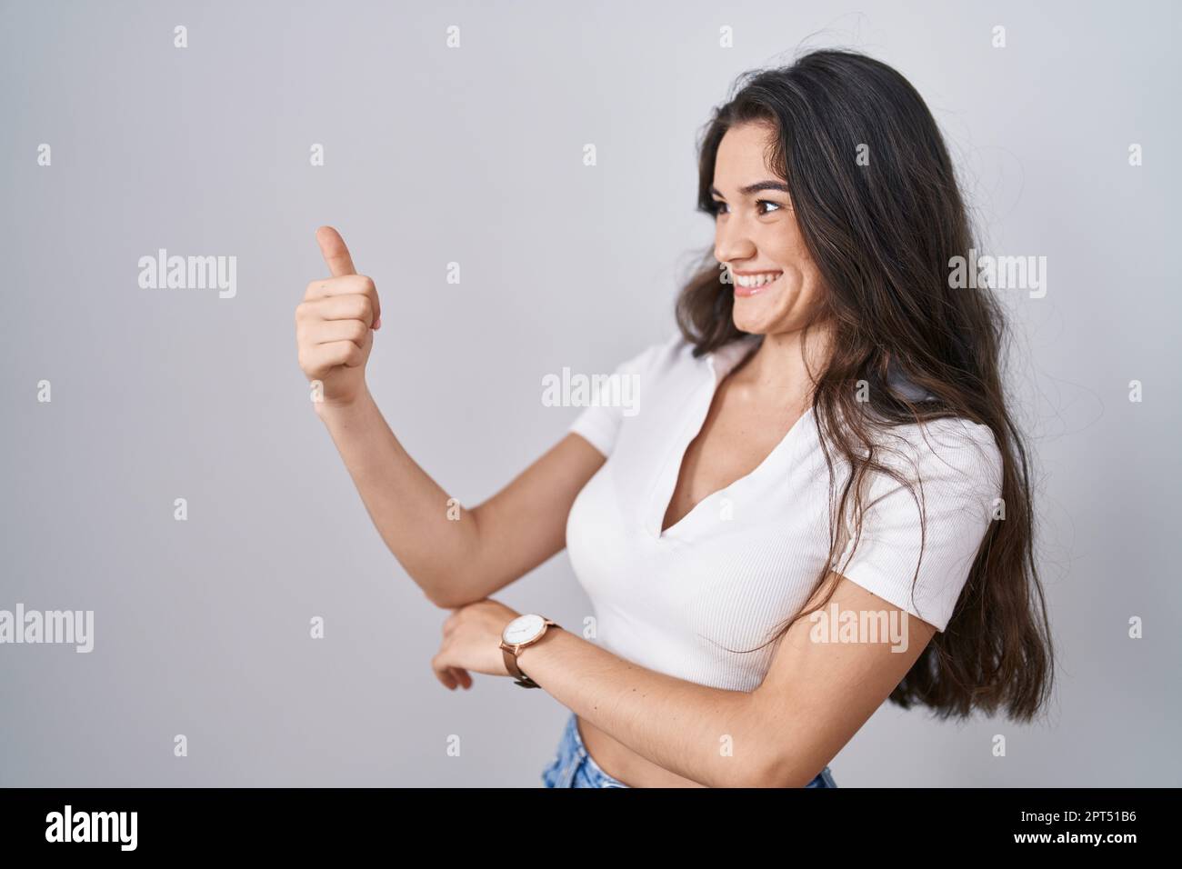 Young teenager girl standing over white background looking proud ...