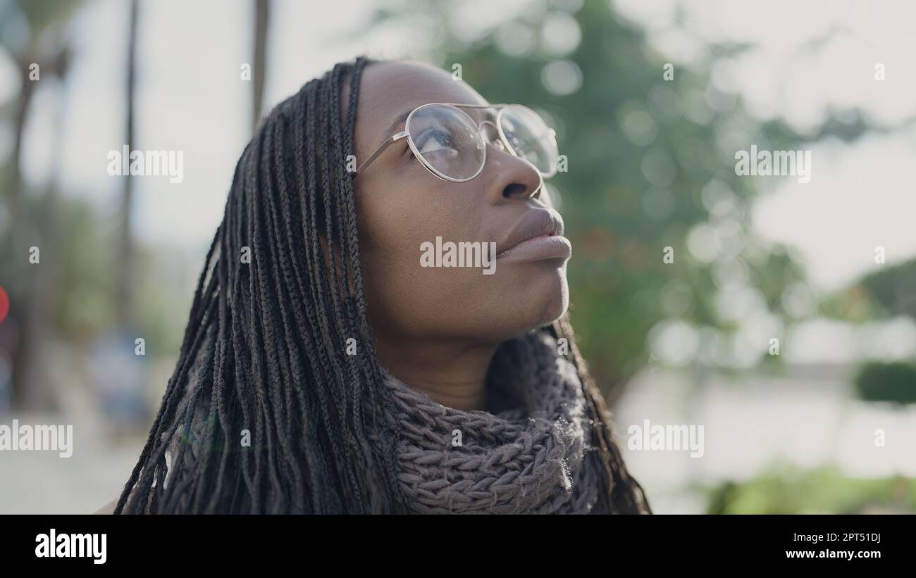 African woman looking up with serious expression wearing glasses at ...